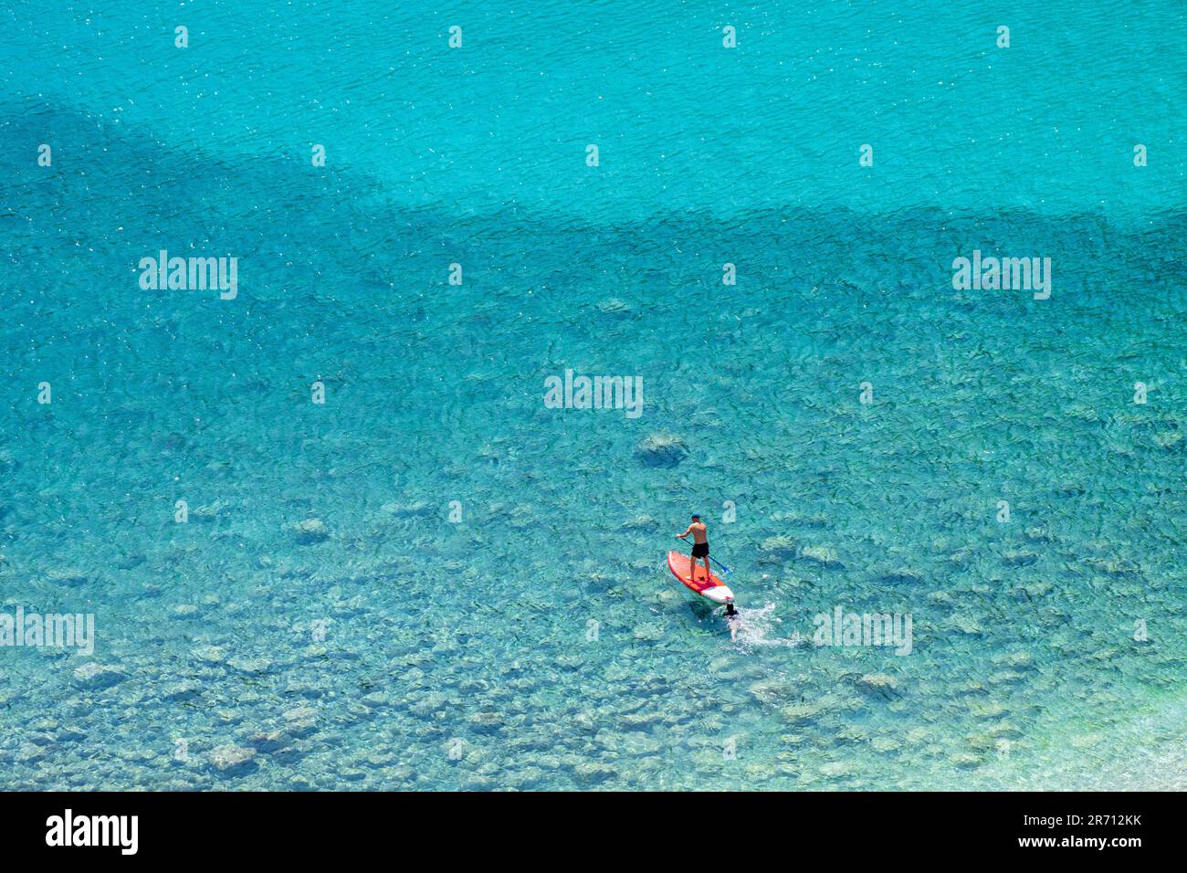 Paddling on surfboard in crystal clear water Stock Photo - Alamy