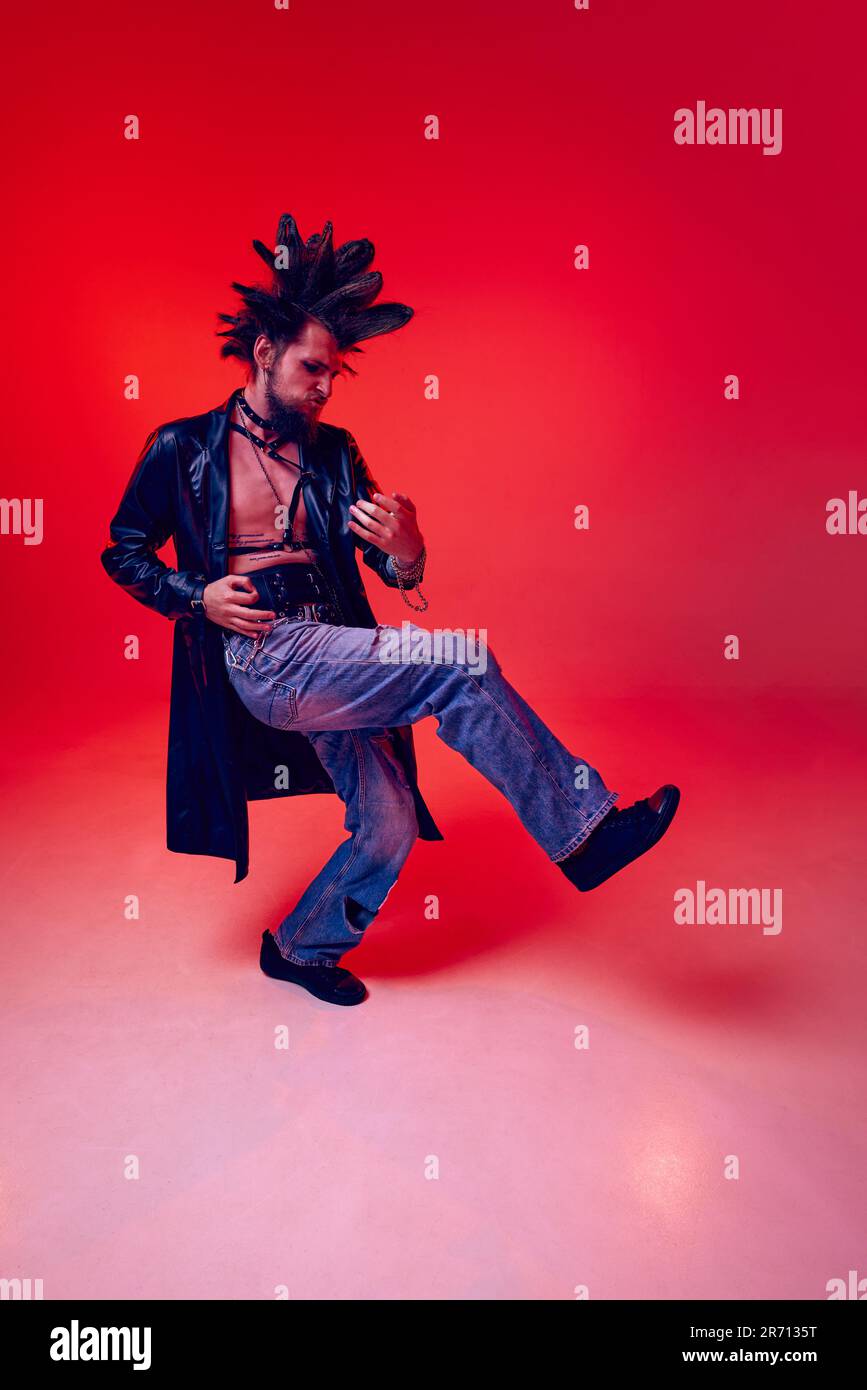 Emotional young man punk in extraordinary clothes, with makeup playing ...