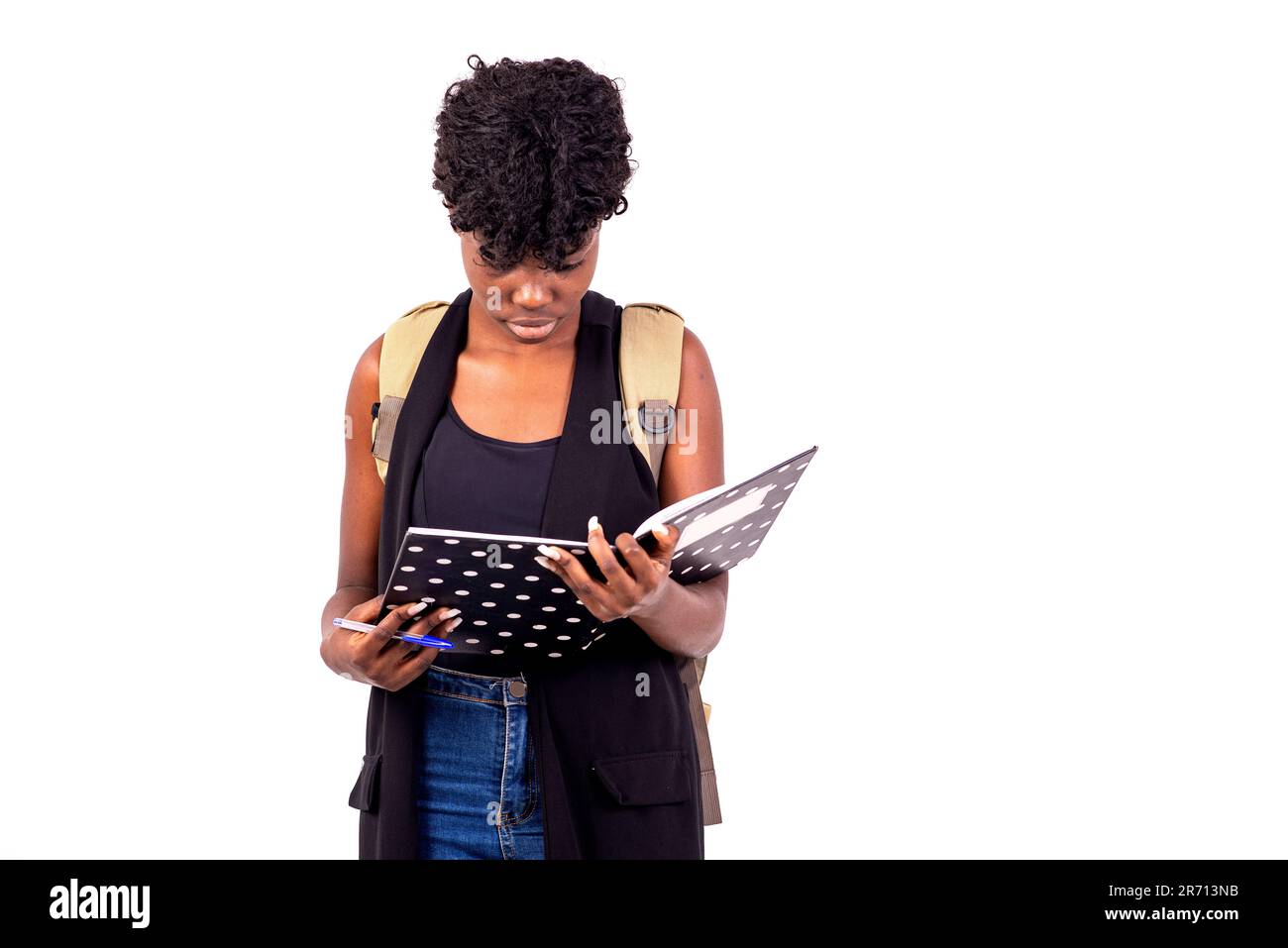 young concentrated student girl carrying a backpack and reading a book ...
