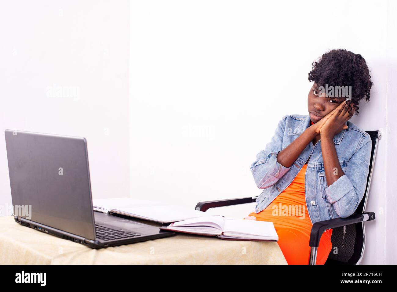 young sad student girl sitting on the table facing computer and holding ...