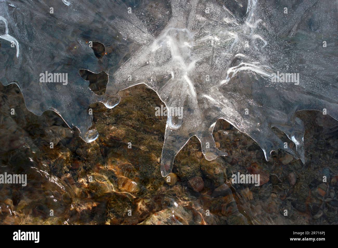 Ice over frozen stream with flowing water Stock Photo - Alamy