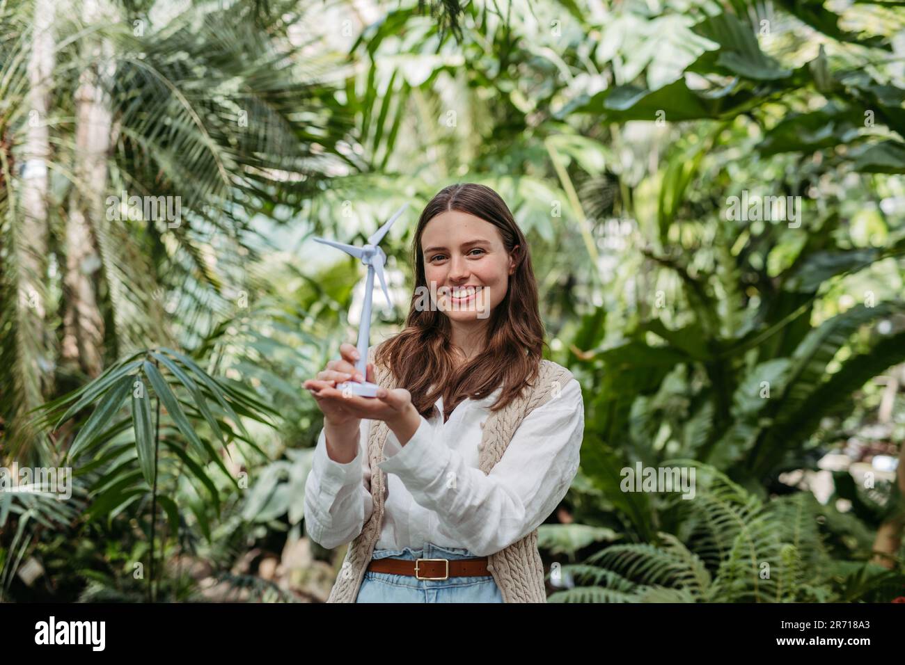 Young woman in jungle holding model of wind turbine, concept of ...