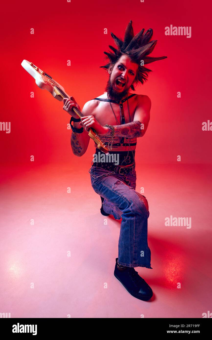 Crazy punk. Emotional young man, rock musician posing aggressively with ...