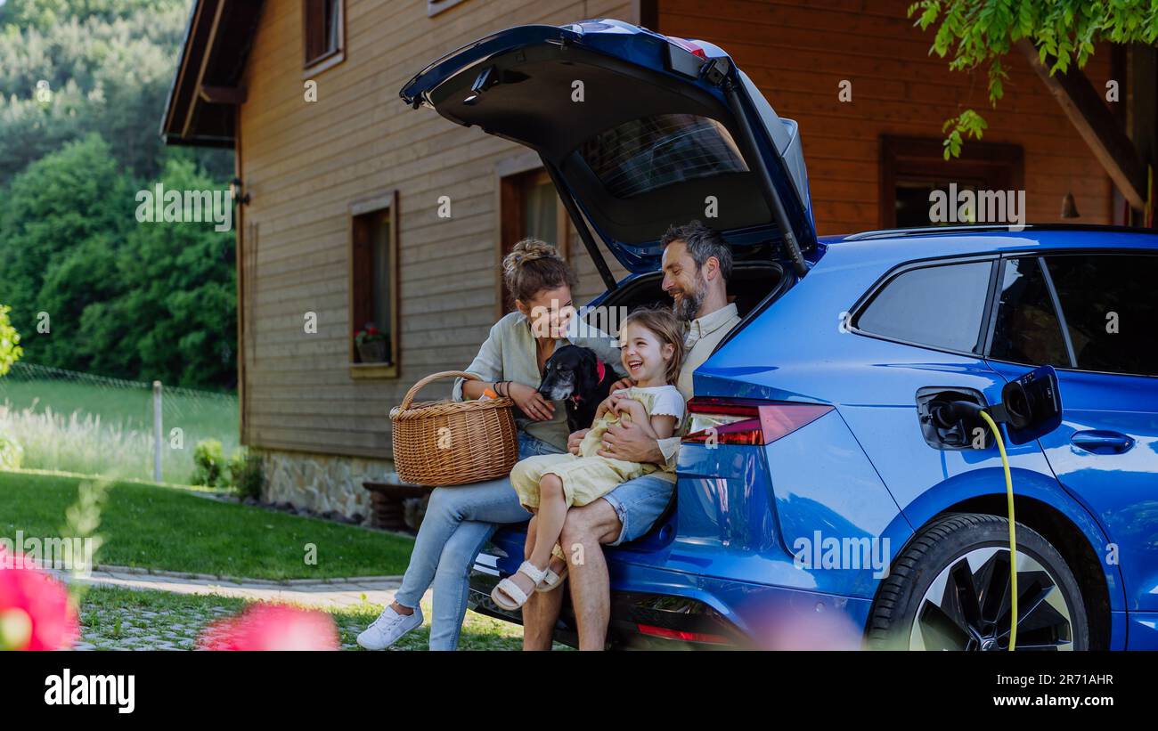 Happy family sitting in a car trunk and waiting for charging Stock ...