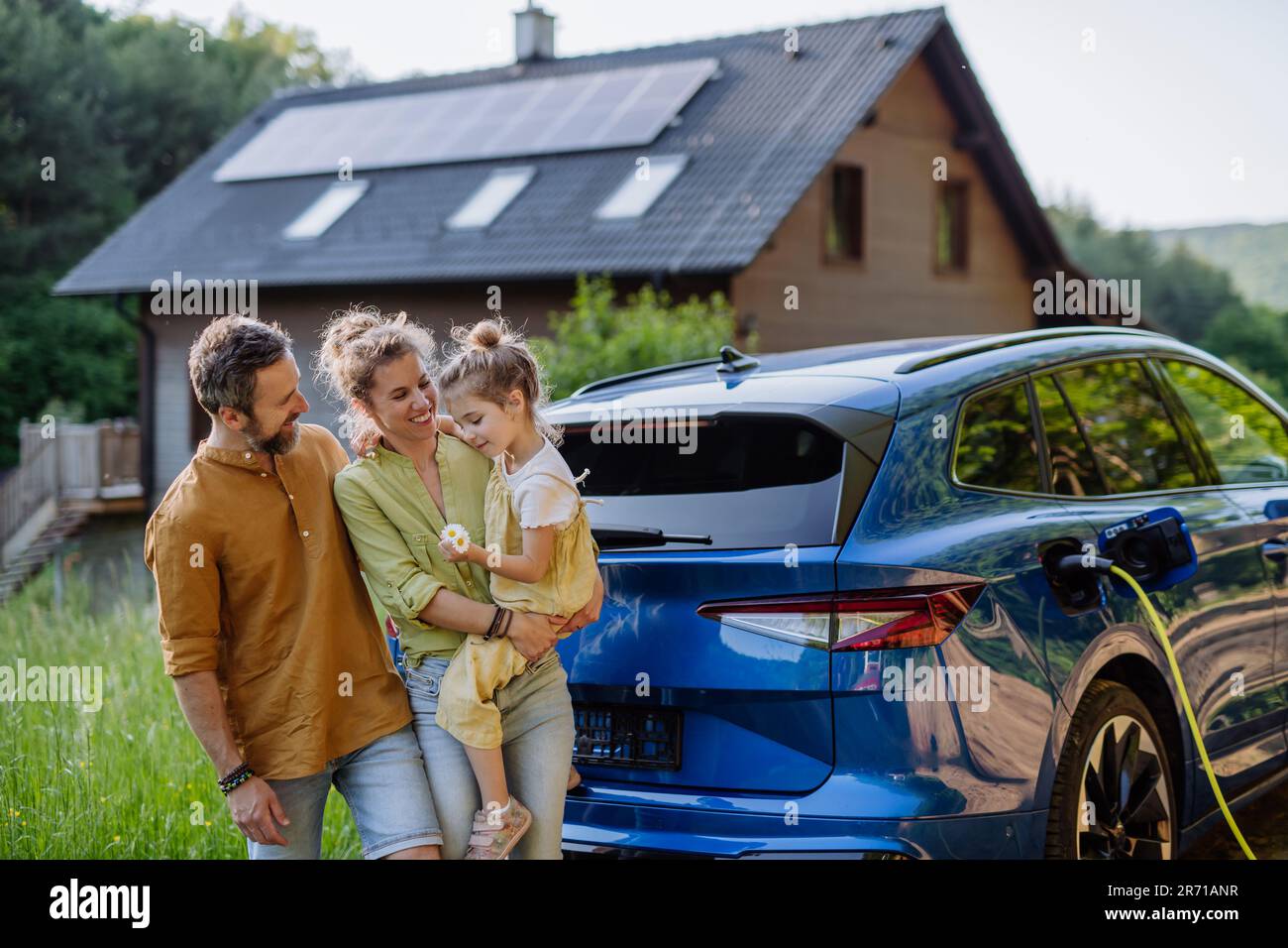 Family with little girl standing in front of their house with solar ...
