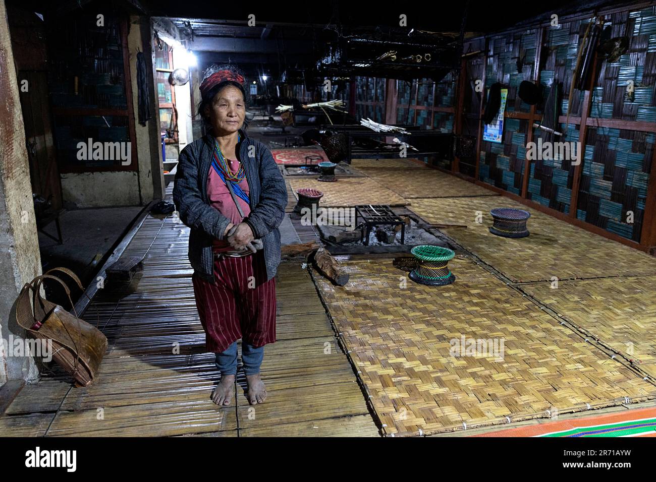 Local woman from a Nyishi tribe standing in a traditional long house ...