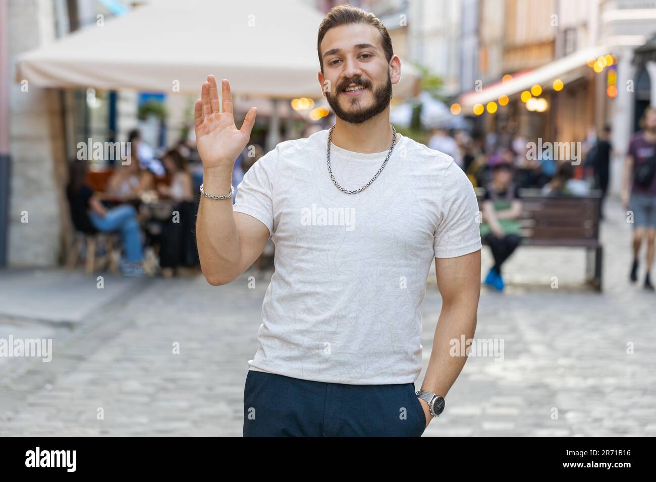 Portrait of bearded young man smiling friendly at camera, waving hands ...
