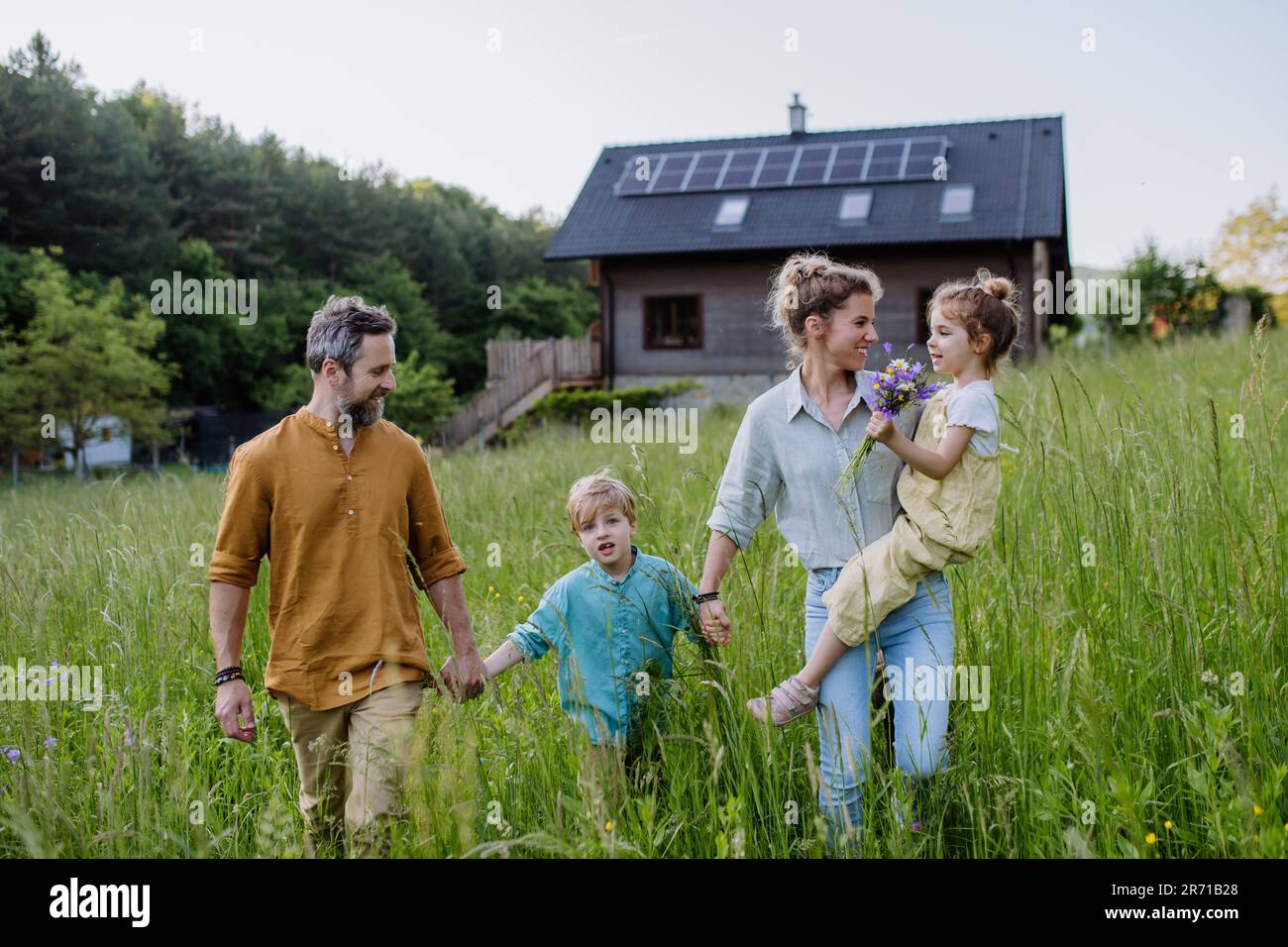 Happy family in front of their house with solar panels on the roof ...