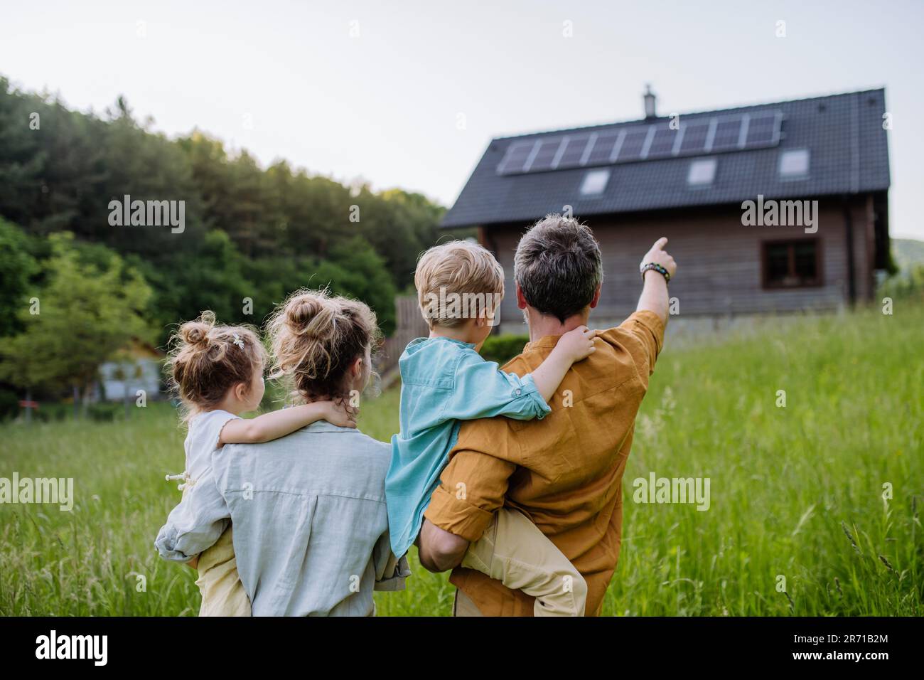 Happy family in front of their house with solar panels on the roof ...