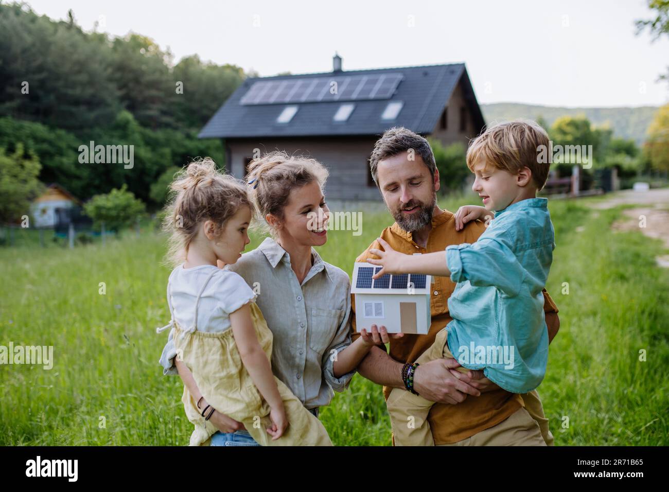 Happy family in front of their house with solar panels on the roof ...