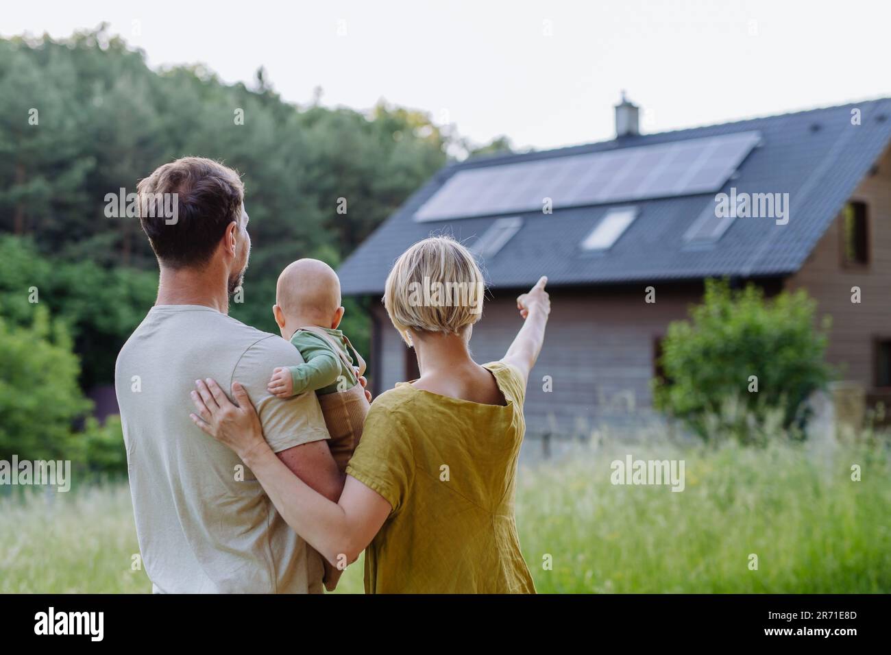 Rear view of family near their house with solar panels. Alternative ...