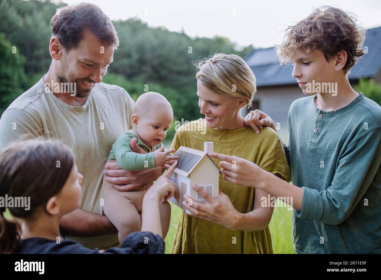 Happy family with three children holding model of house ith solar ...