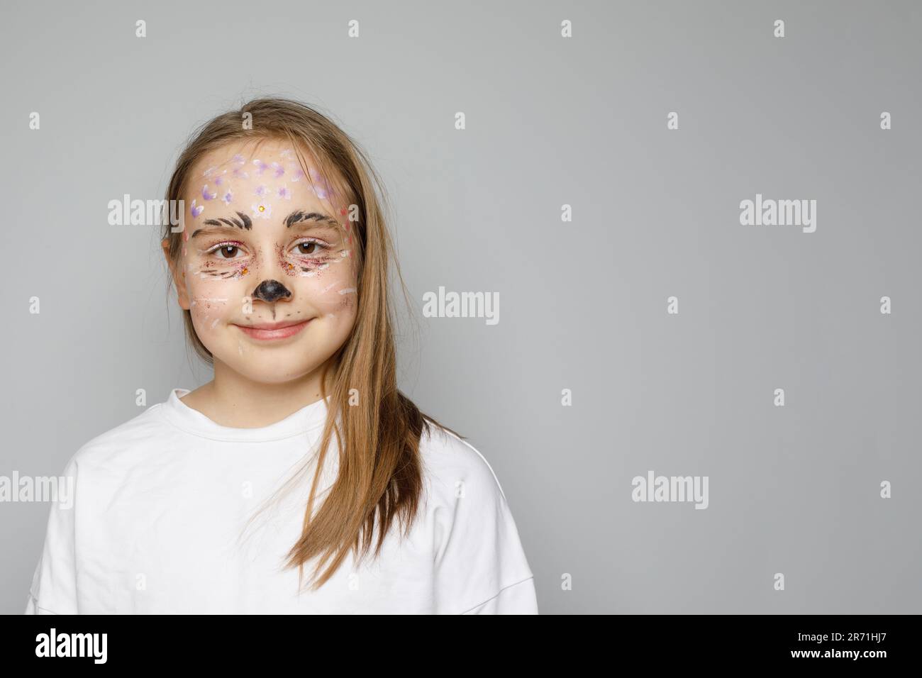 Cute funny child with paint on face smiling against grey studio wall ...