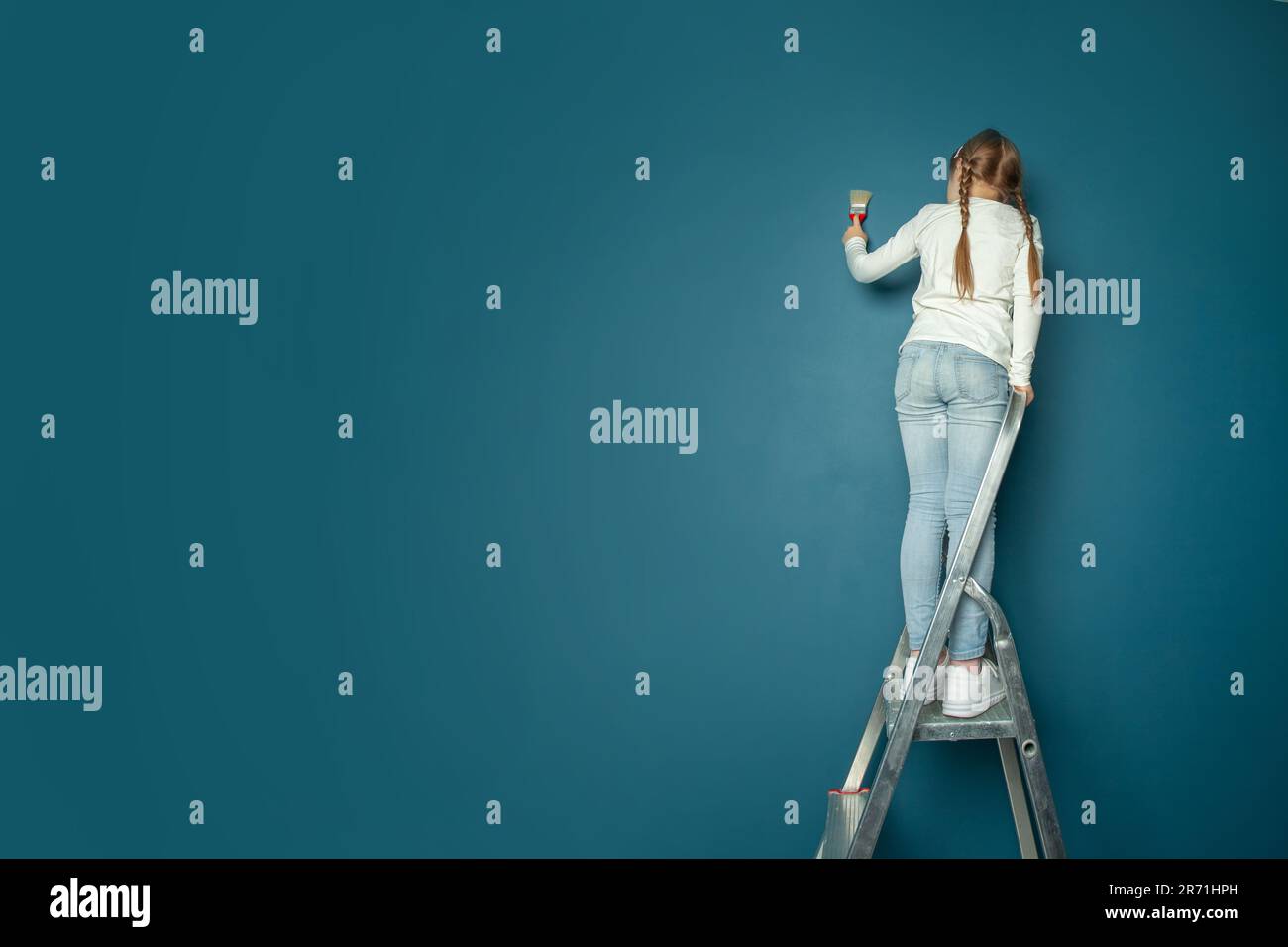 Child girl painting wall, doing renovation with brush and standing on ...