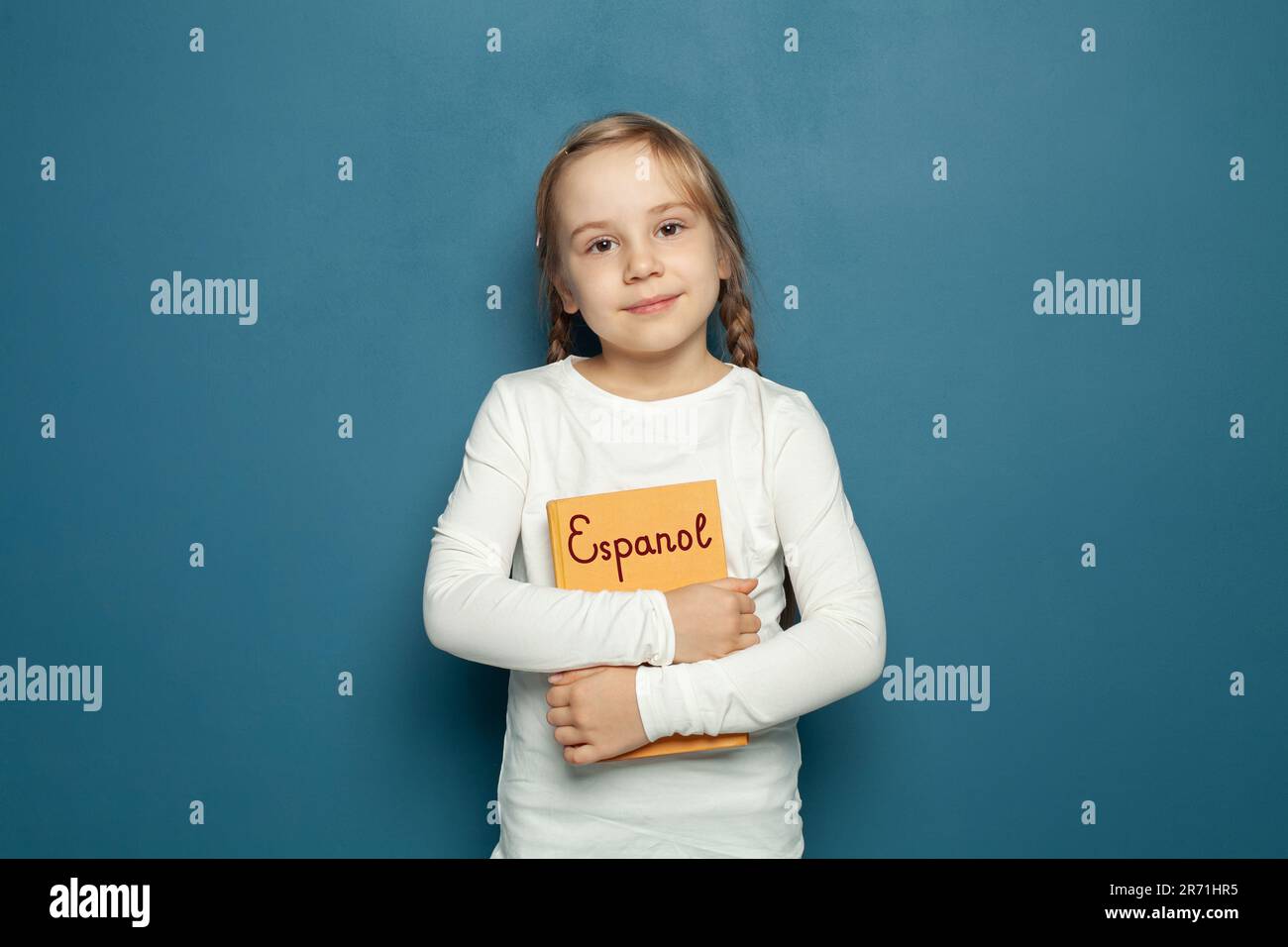Child student girl with Spanish language book on the background of blue ...