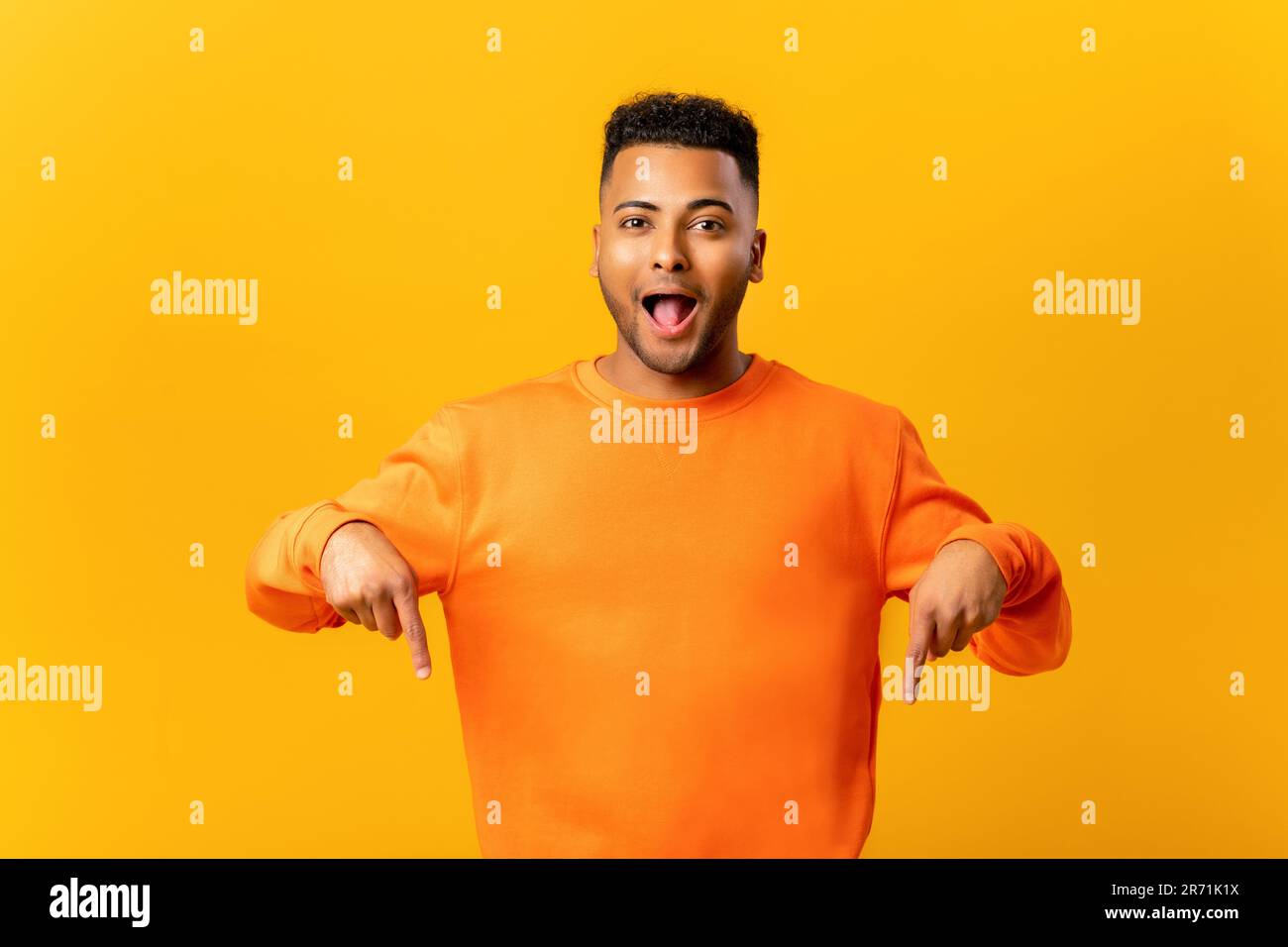 Shocked wondered man showing direction pointing fingers down at empty ...