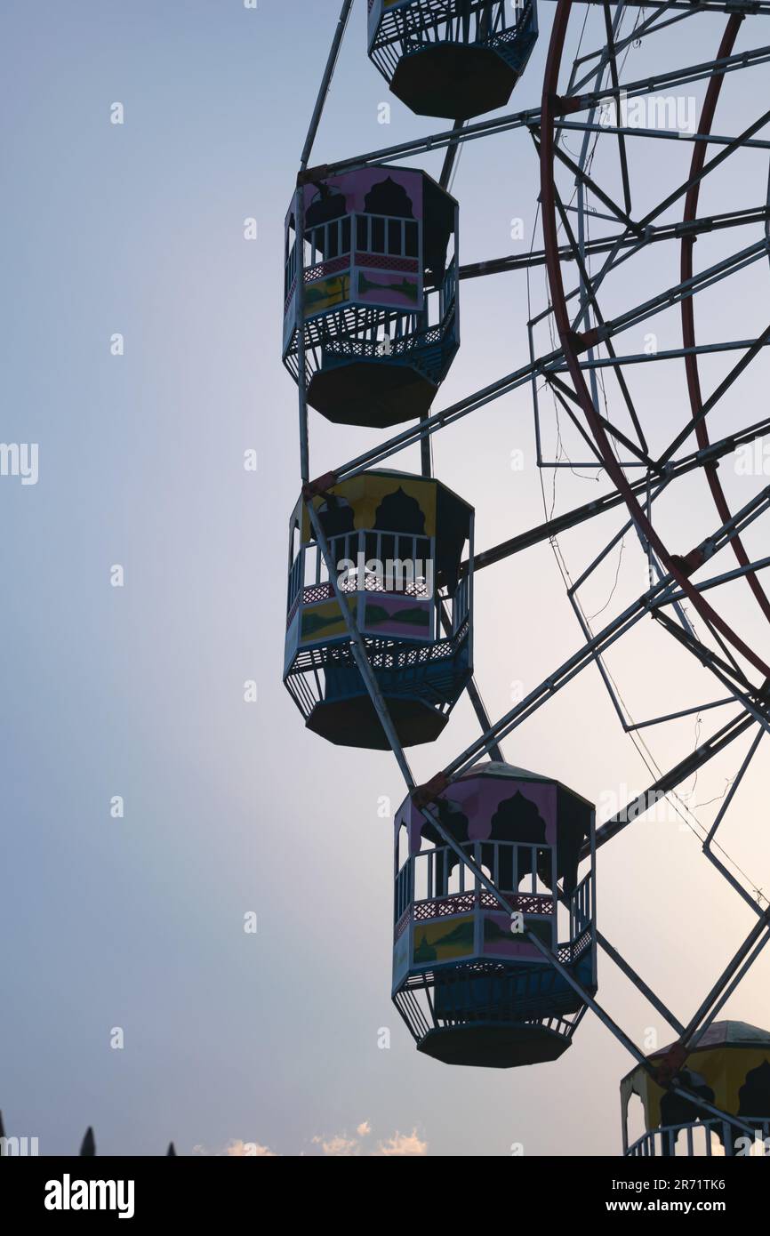 A picturesque Ferris wheel stands atop a grassy hill, with four carts ...