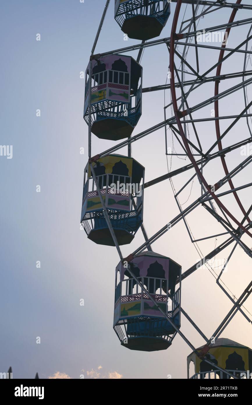 An outdoor ferris wheel with three vibrant colored carriages against a ...
