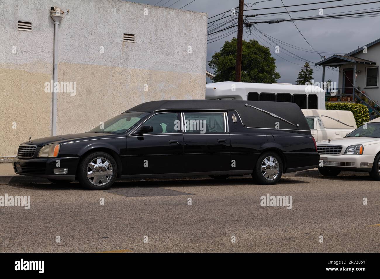 Black and a white Cadillac Hearse parked on the street in front of a ...