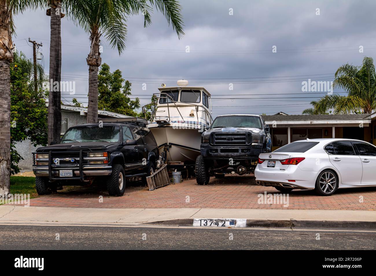 Pickup trucks and a fishing boat parked on a residential street ...