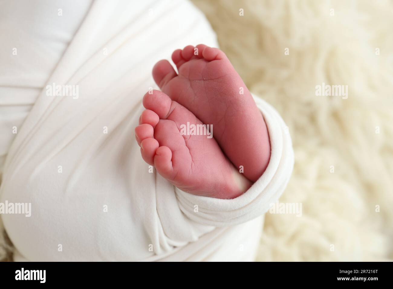 Tiny foot of a newborn. Soft feet of a newborn in white woolen flaccati ...