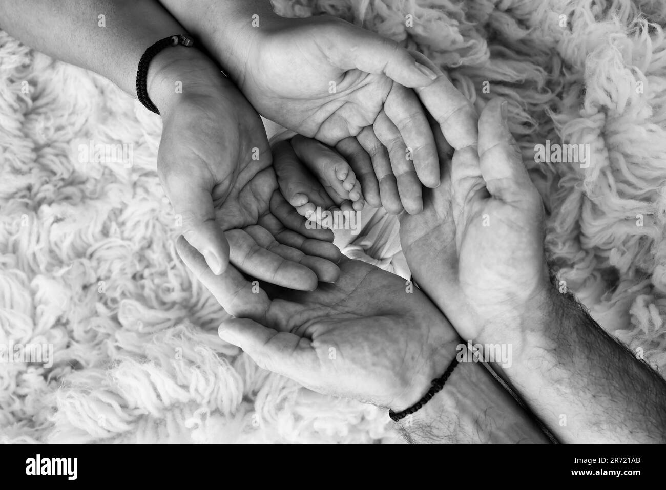 The palms of the father and mother are holding the foot of newborn baby ...