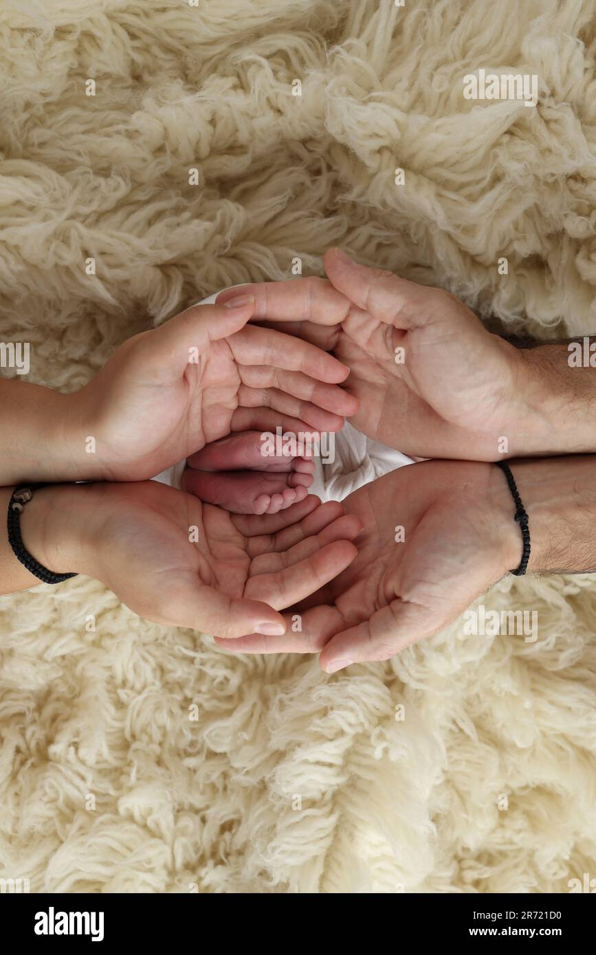 The palms of the father and mother are holding the foot of the newborn ...