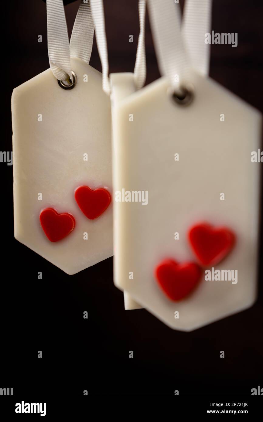 Two red heart-shaped tags hang from a white ribbon, creating a romantic ...