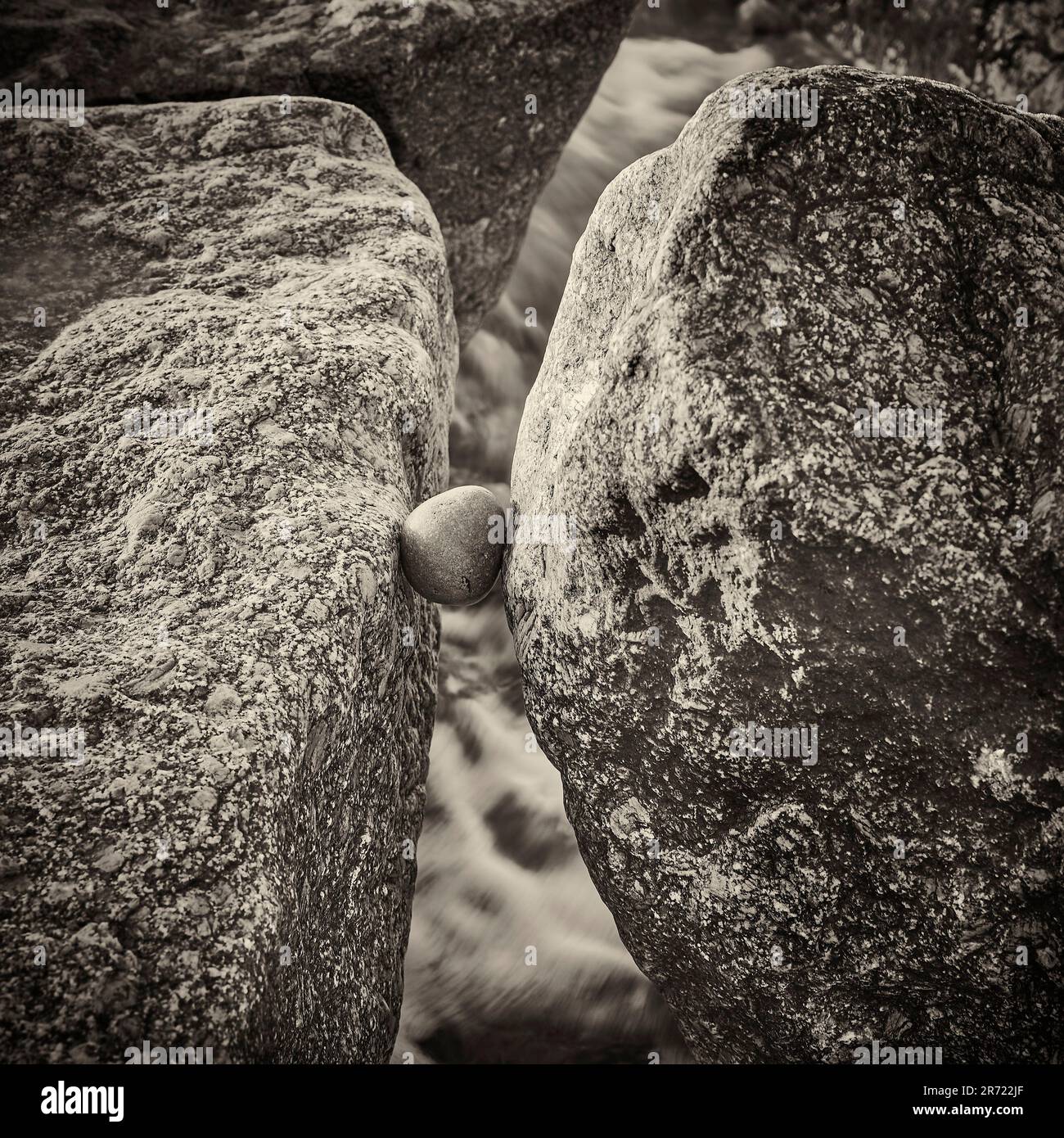Pebble wedged between two large rocks Stock Photo - Alamy