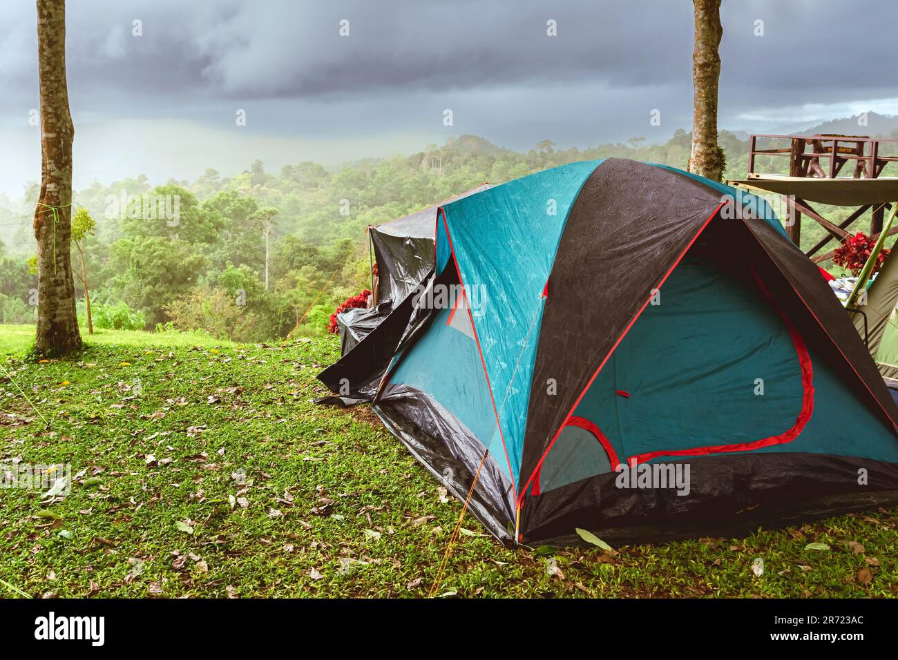 Camping activities in rain-filled holiday. Tent on campsite by the hill ...