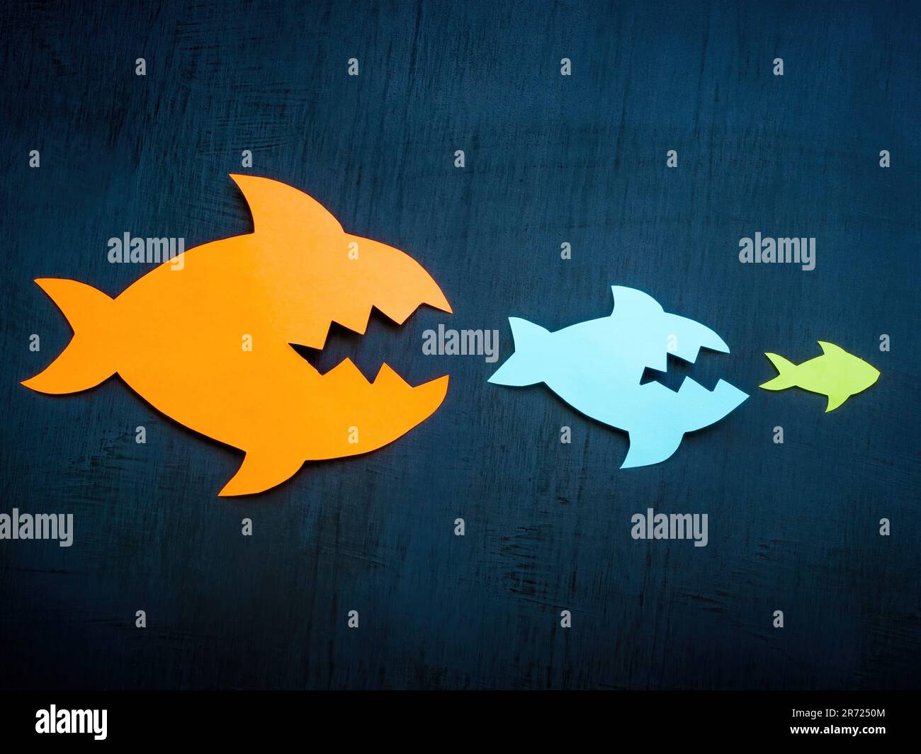 Paper fish are trying to eat each other. Concept of merger and ...