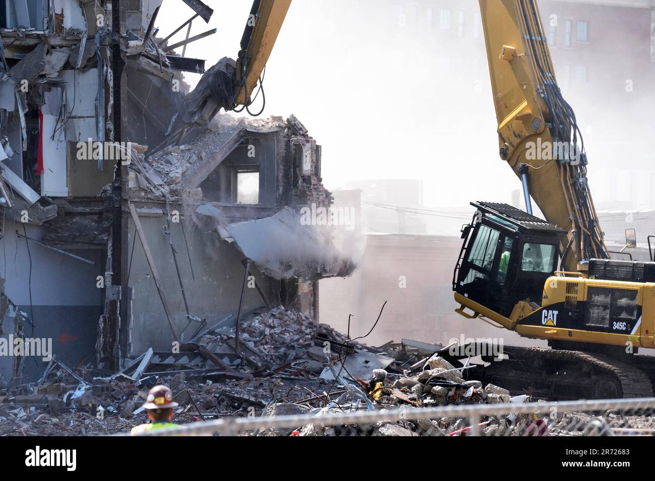 A worker watches debris fall during demolition at the site of a ...
