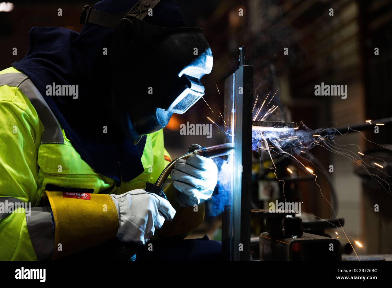 A mechanic in a warehouse environment is wearing a protective face mask ...