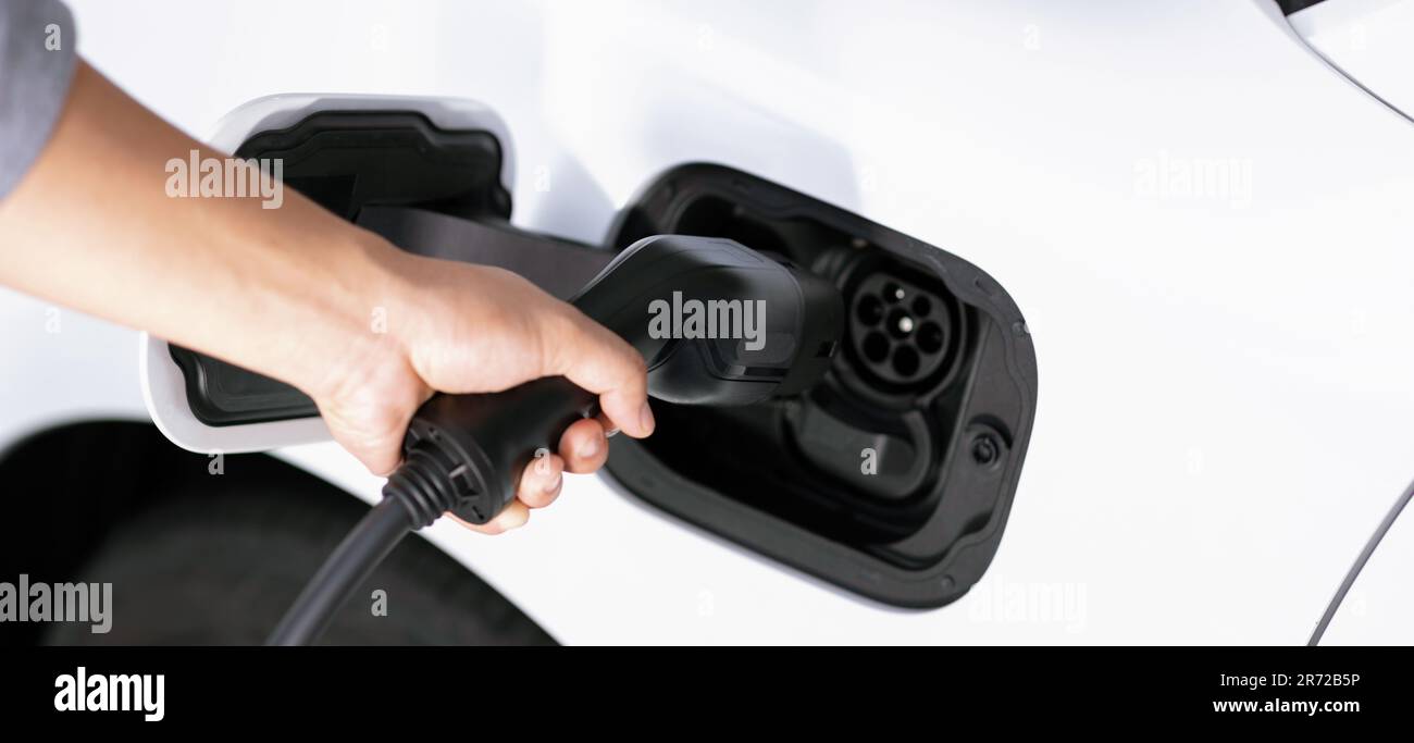 Closeup focus hand insert EV charger plug to electric vehicle from ...