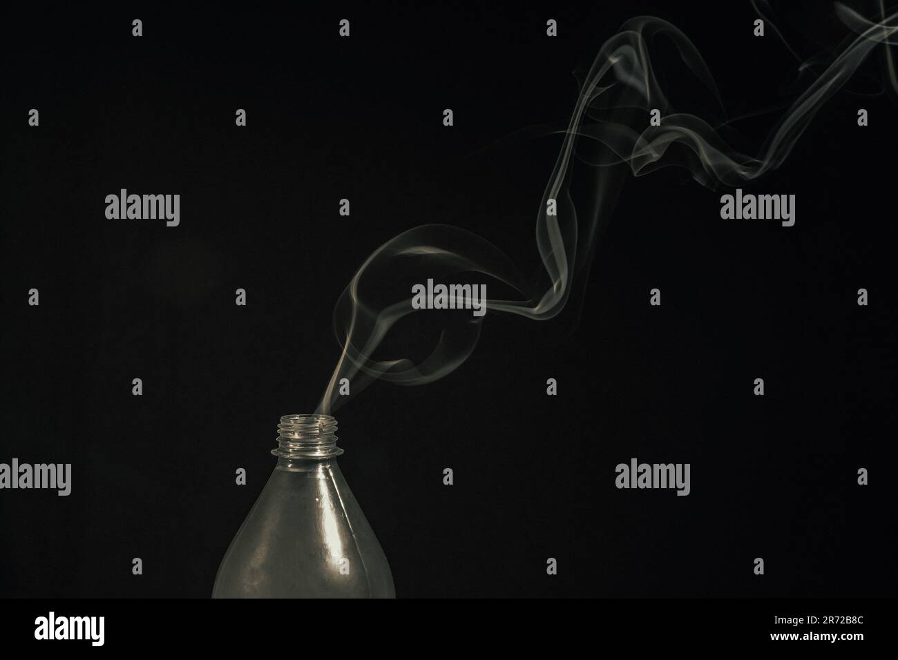 A plastic bottle with its lid off emits a plume of smoke into the air ...