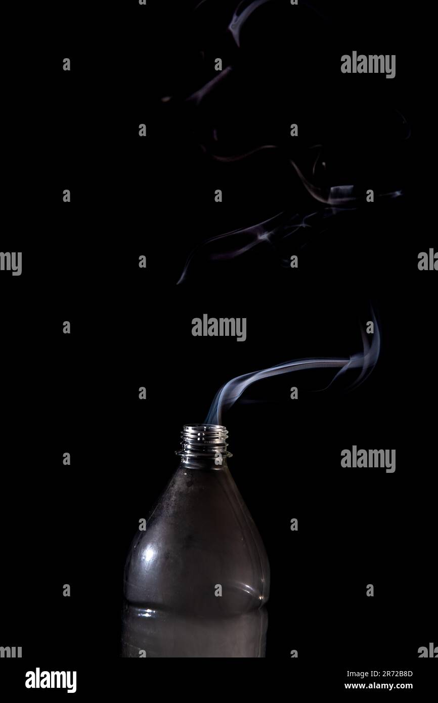 A plastic bottle with its lid off emits a plume of smoke into the air ...