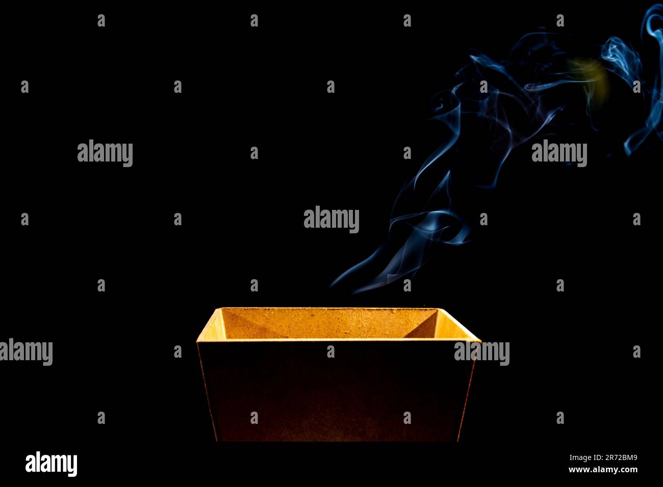 A glowing container emitting a plume of smoke into the air on the dark ...