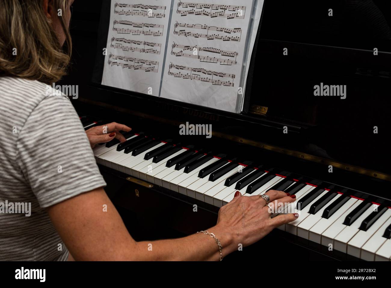 A female musician seated at a grand piano playing a melodic tune, with ...