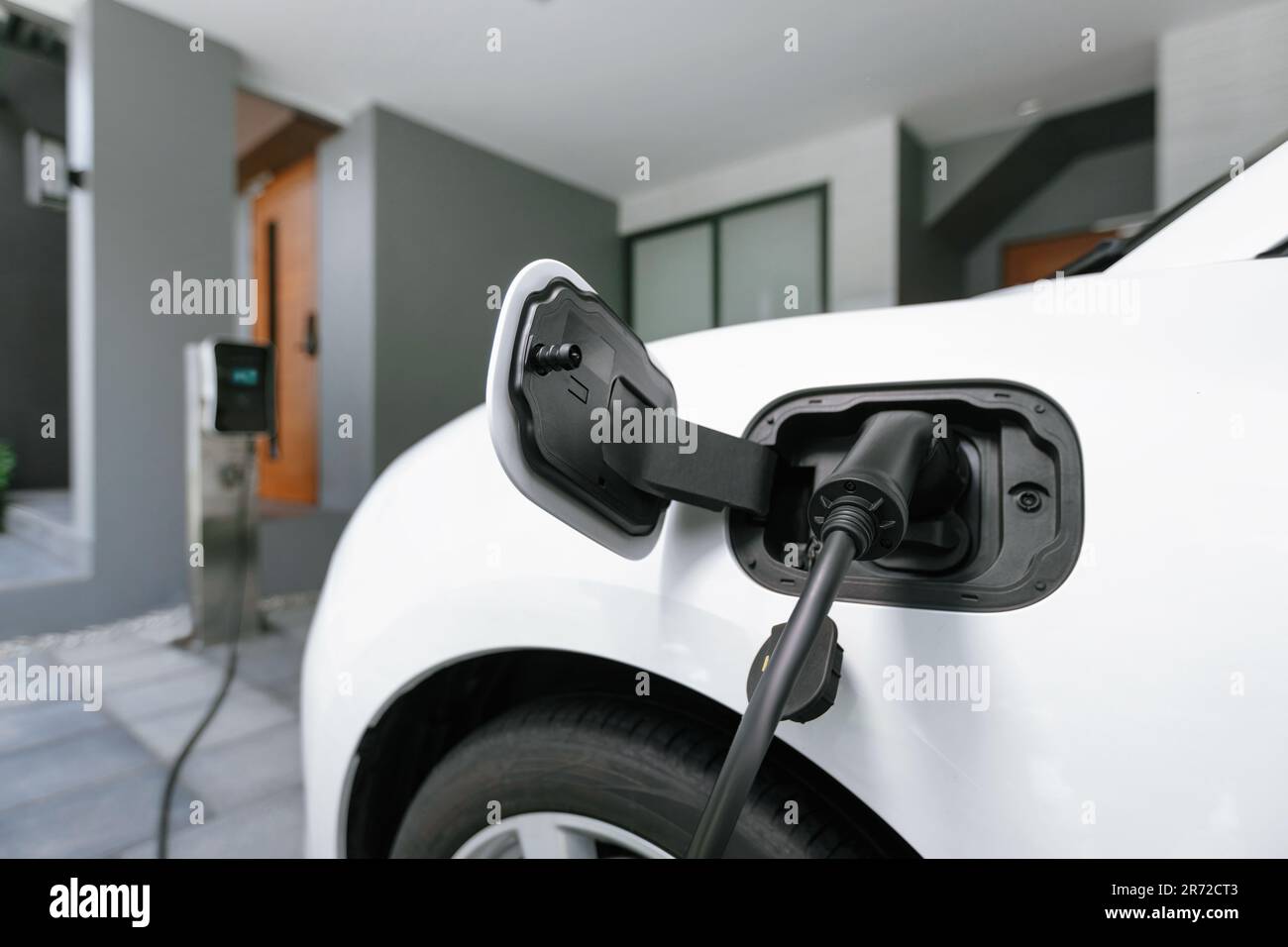 Closeup electric vehicle plugged-in with cable from charging point ...