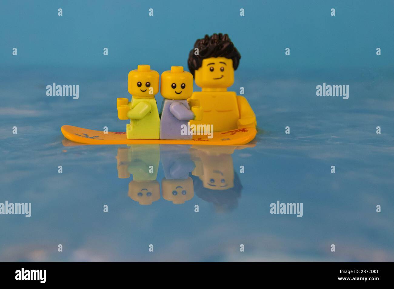 A family of LEGO figures and toys seated atop a floating board in a ...