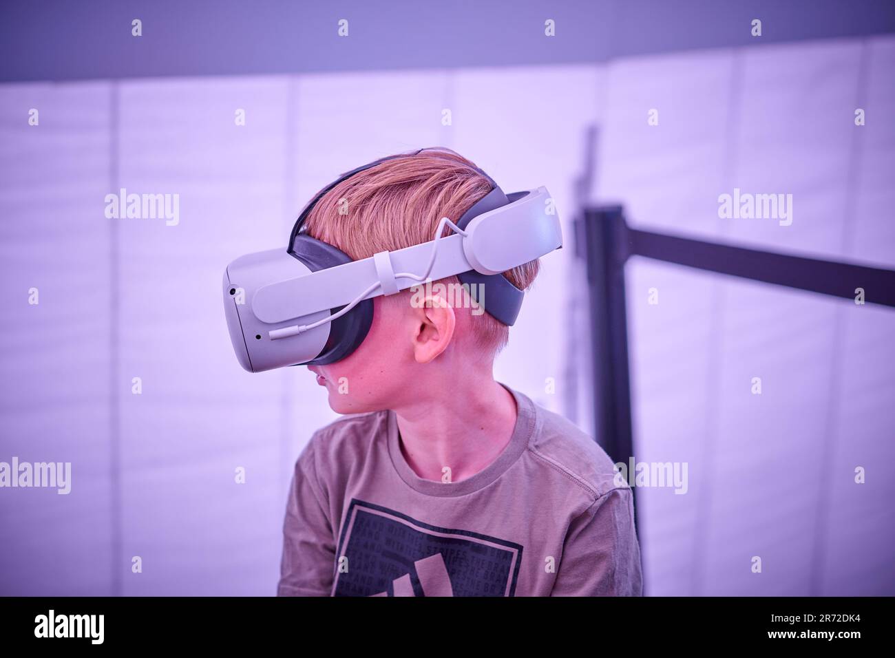 A young boy wearing a Virtual Reality head device on a plain white ...