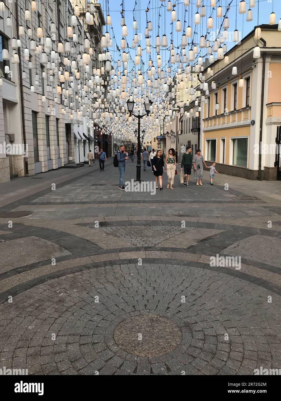 A group of people walking through a lit city square at night ...