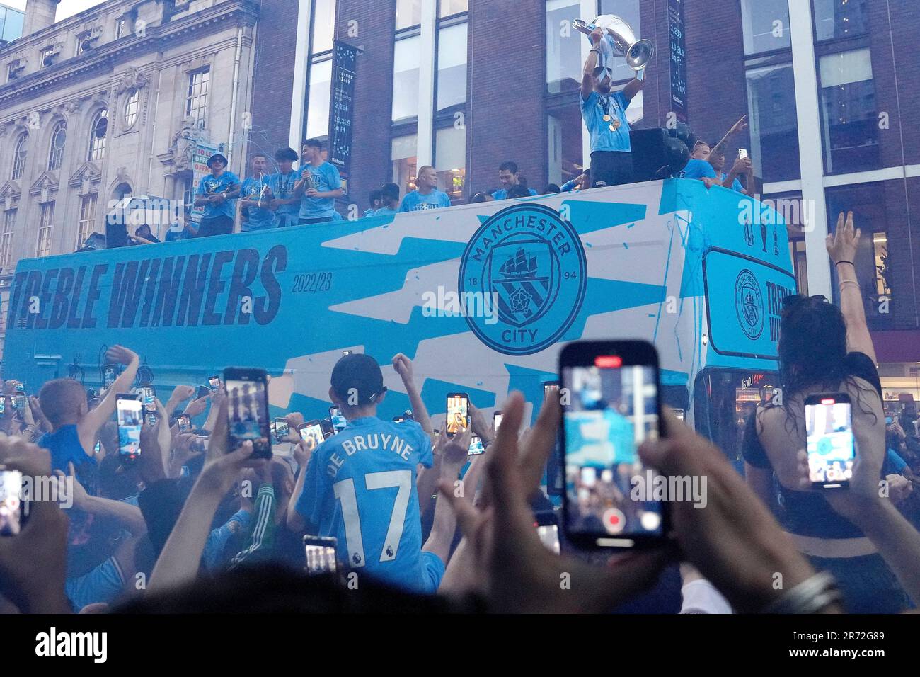 Manchester City soccer players celebrate with the trophies on top of a ...
