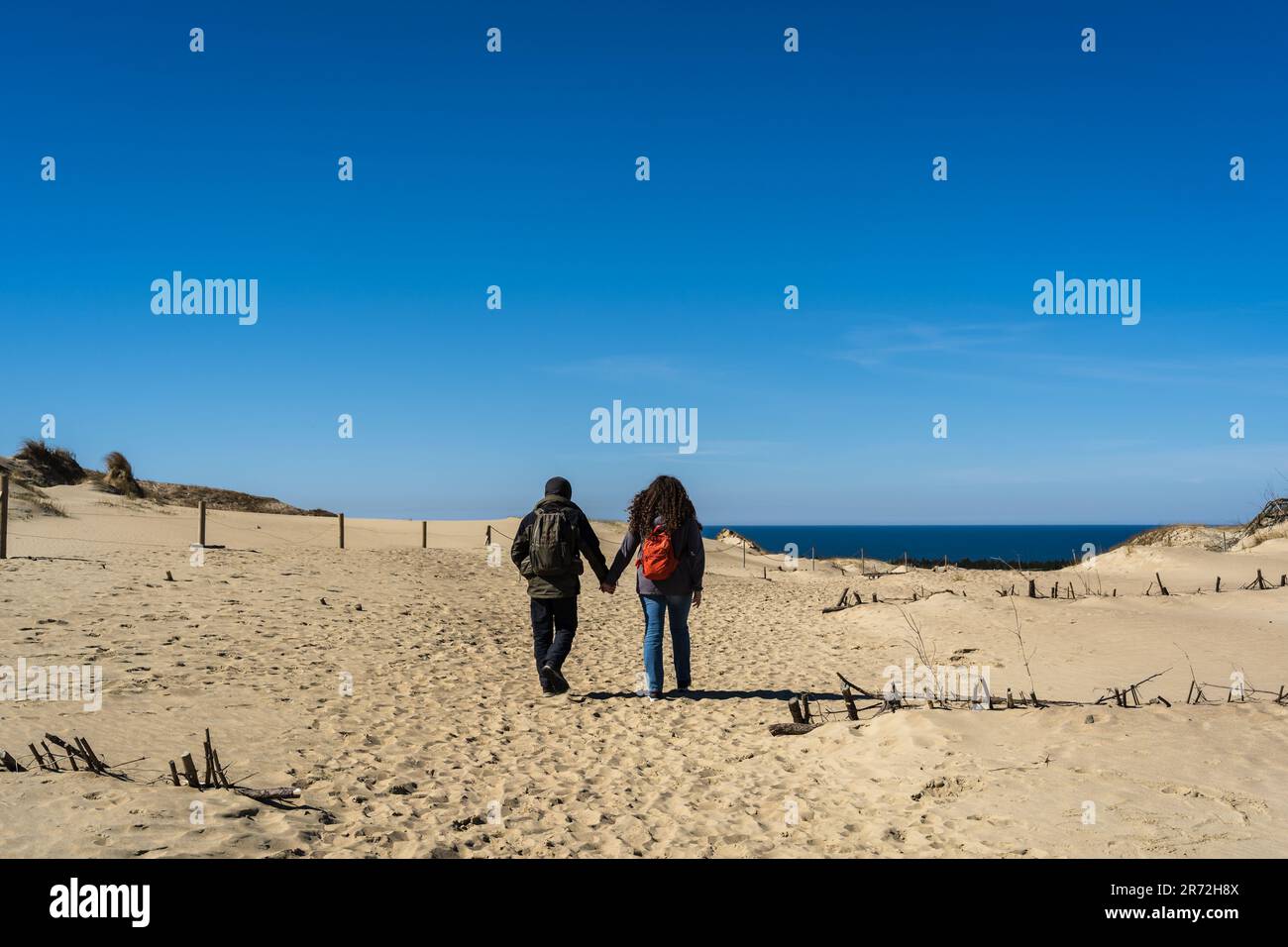 A couple of travelers with a backpack, hand in hand, walks along the ...