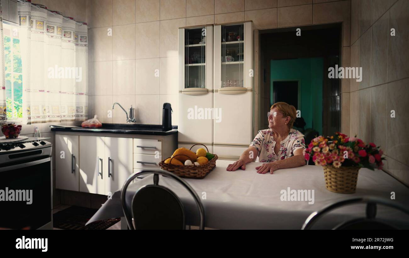 Lonely senior woman sitting alone in kitchen table. Old age lifestyle ...