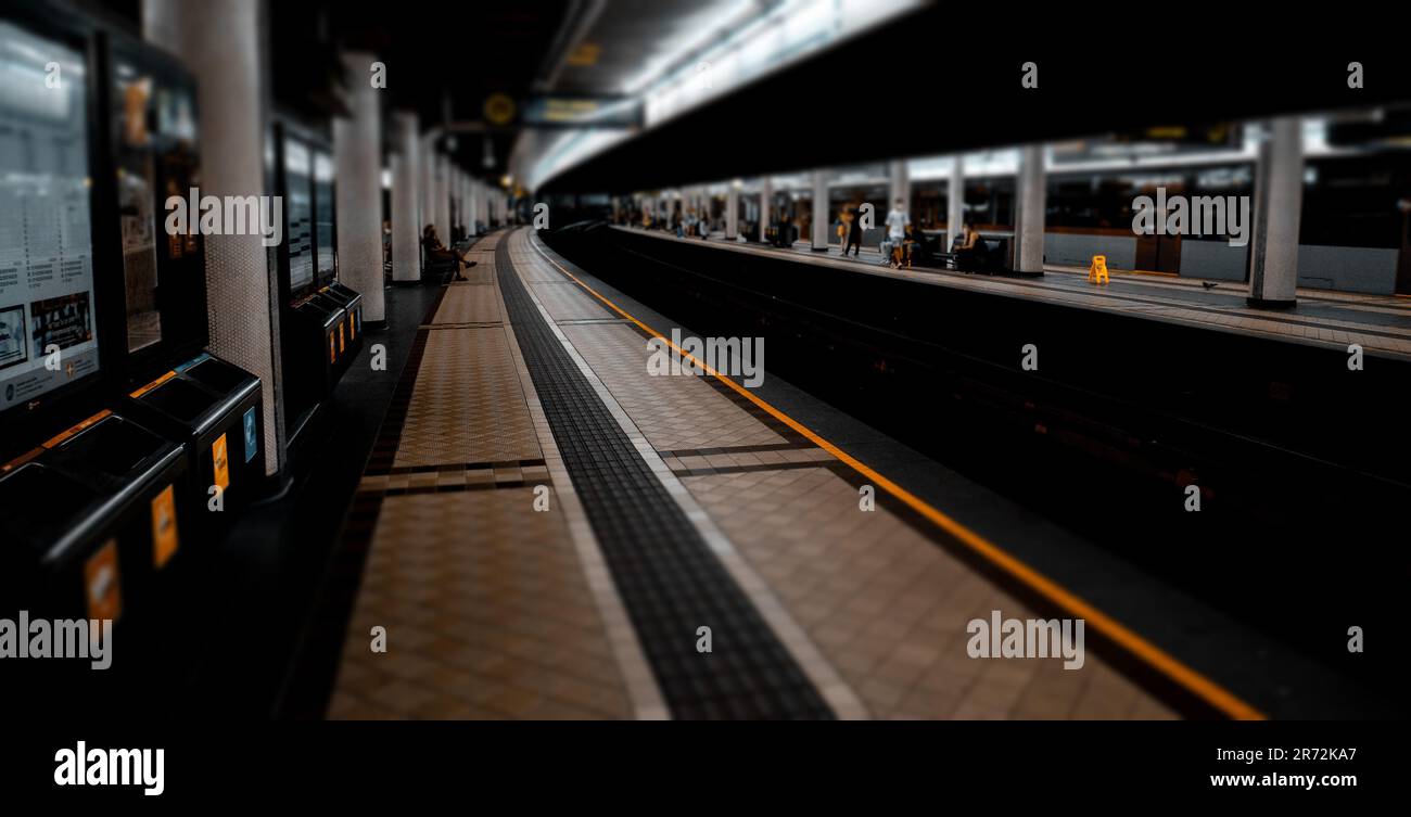 An empty subway platform in a bustling city, illuminated by the lights ...