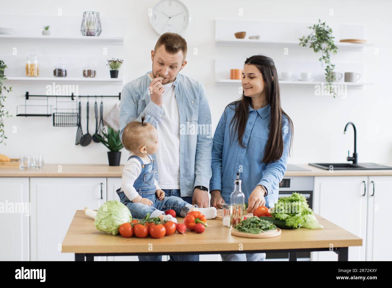 Inquisitive little girl staring at loving parents while dad chewing ...