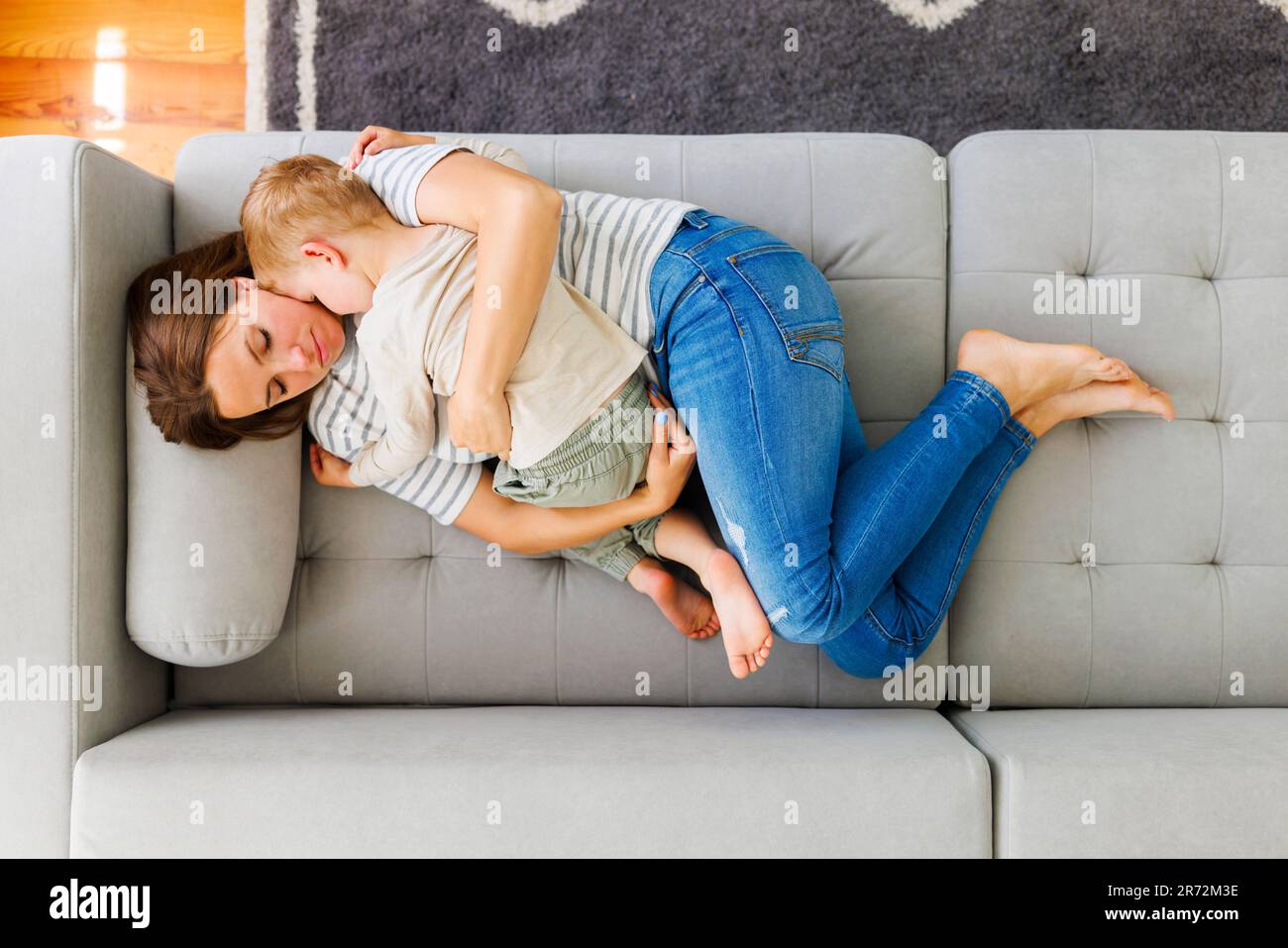 Mother embraces her cute little son while laying together on the couch Stock Photo - Alamy