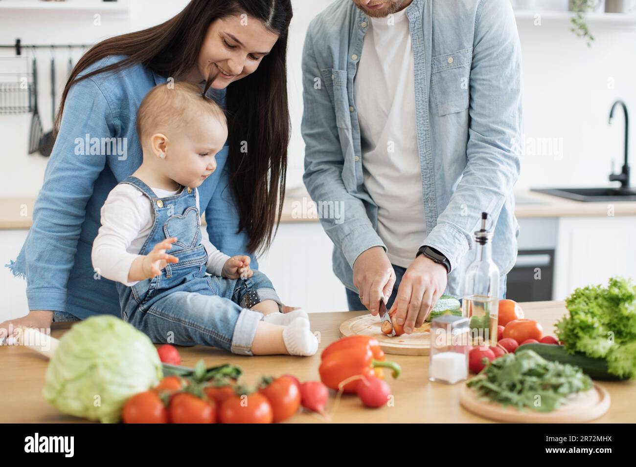 Close up view of male cutting raw vegetable while cute little lady ...