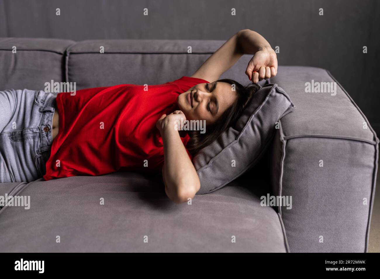 Young pretty woman sitting on couch at house. Female stretching body ...